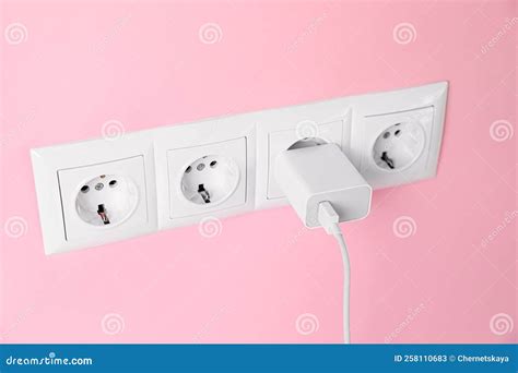 Charger Adapter Plugged Into Power Sockets On Pink Wall Electrical