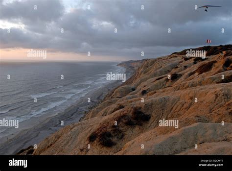 A Hang Glider Soars Above The Dramatic Torrey Pines Cliffs On The