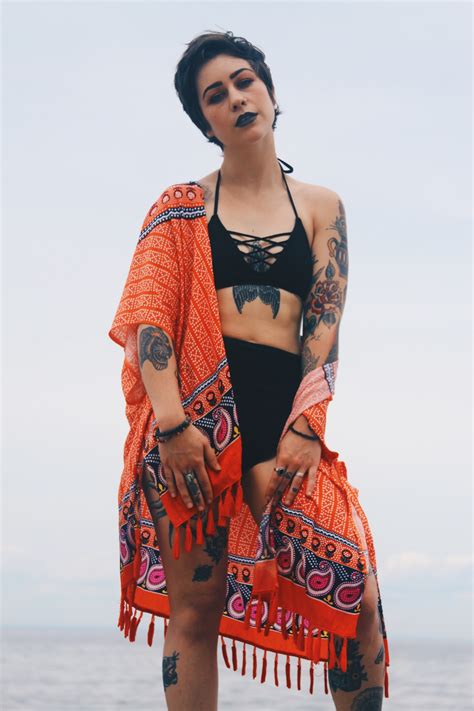 A Short Haired Woman In A Black Bikini Wearing An Orange Cover Up By