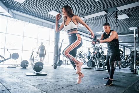 Young Sportive People Doing Exercises Together In The Gym Woman Running When Man Holding Her By