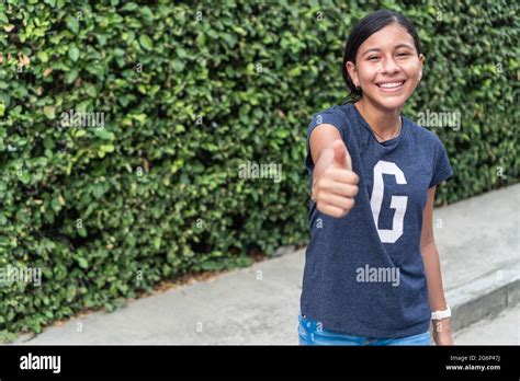 Hispanic Teenager Making Positive Hand Gesture Thumbs Up Smiling And