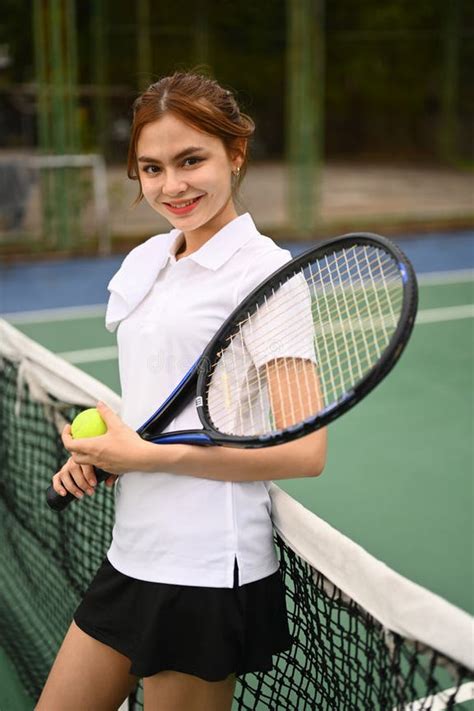 Retrato De Una Sonriente Tenista Femenina Con Raqueta Y Pelota Parada En La Red En La Pista De