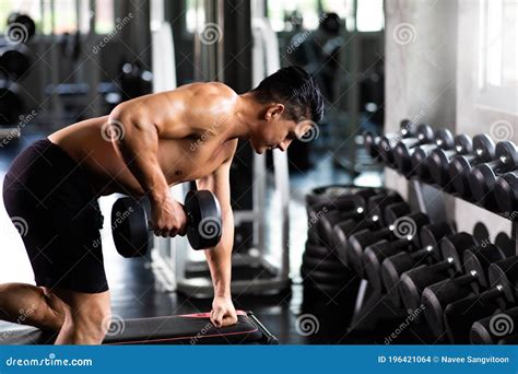Young Man Naked Bodybuilder Exercising Lifting With Dumbbell At Gym