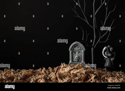 Halloween Background With Tombstone That Have Black Tree And Blurred Ghost With Dried Grass On