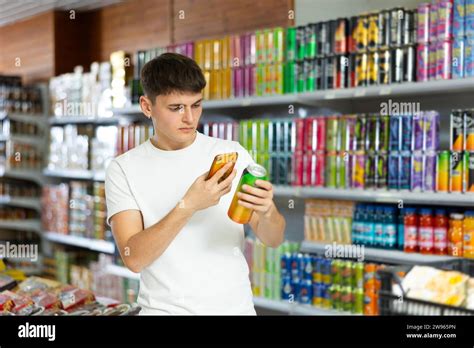 Guy Scans Bar Code From Label Of An Aluminum Can With Drink In Grocery