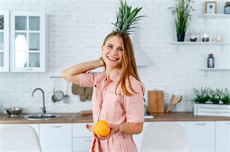 Une Femme Se Tient Dans Sa Cuisine Et Tient Une Orange Prête à L