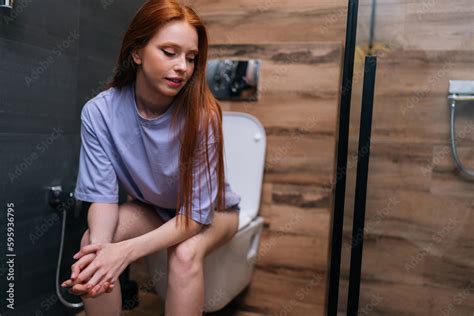 Positive Young Woman In Casual Clothes Sitting On Toilet Bowl At Home
