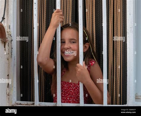 Cute Teenage Caucasian Smiling Girl With Braces Looking At The Camera Behind The Bars Of A Door