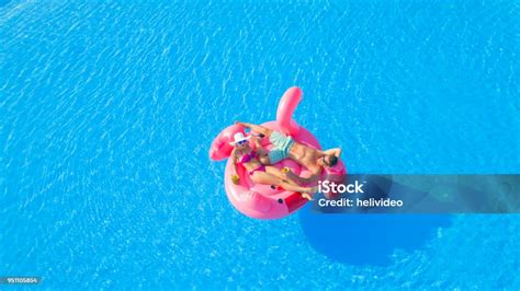 Aerial Guy And Girl Relaxing Sipping Cocktails On Fun Flamingo Floatie
