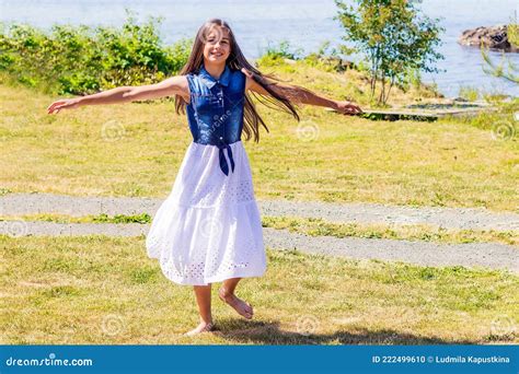 A Pretty Smiling Girl In A Light Summer Dress With Bare Feet Is Dancing