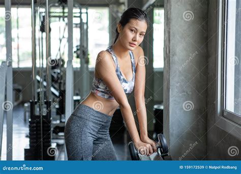 Asian Sport Girl Standing In Front Of Dumbbells Shelf Workout In The
