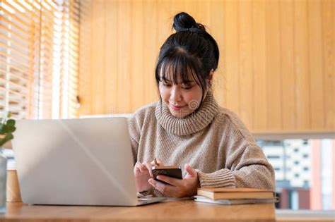 A Positive Asian Woman Is Checking Messages On Her Smartphone While