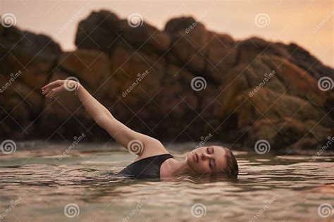 Woman In Black Swimsuit Enjoys Serene Sea Dip At Sunset Ocean Bathing