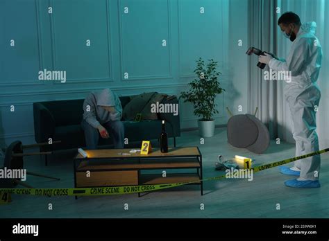 Forensic Expert With Camera Working And Victim At Crime Scene Indoors