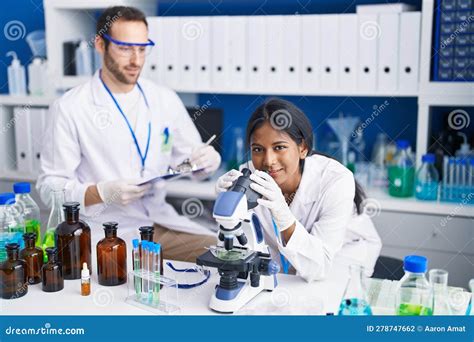 Man And Woman Scientists Using Microscope Working At Laboratory Stock