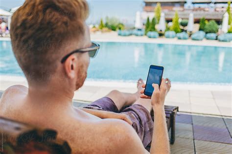 Man Texting By The Swimming Pool By Stocksy Contributor Lumina