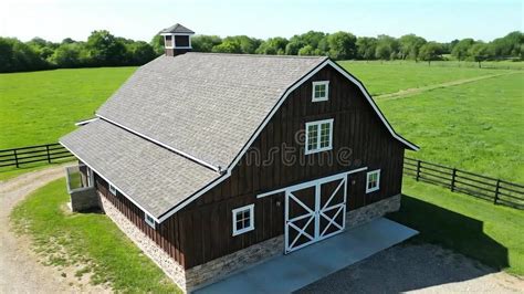 Dark Brown Wooden Barn With Stone Foundation Set In A Lush Green Grassy