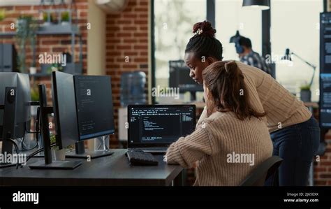 two system engineers analyzing source code on laptop looking for errors