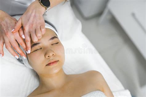High Angle Shot Of A Woman Laying Down With Her Eles Closed And Receiving A Face Massage Beauty