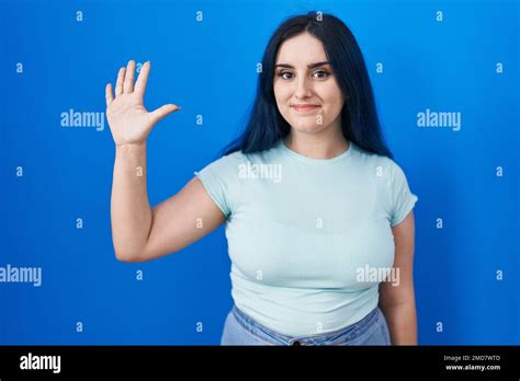 Young Modern Girl With Blue Hair Standing Over Blue Background Showing