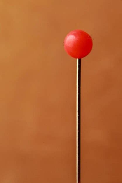 Premium Photo Close Up Of Red Straight Pin Against Brown Wall