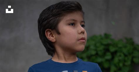 녹색 식물 근처에 서 있는 파란색 크루넥 티셔츠를 입은 소년 사진 Unsplash의 무료 소년 이미지