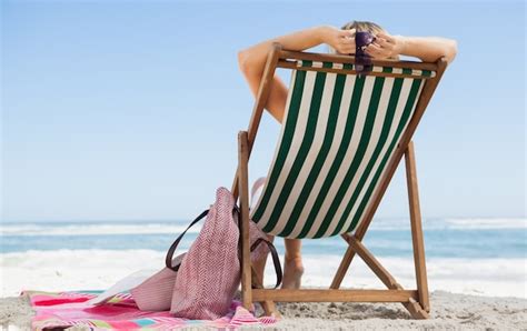 Premium Photo Woman Sitting In Deck Chair At The Beach With Her Beach