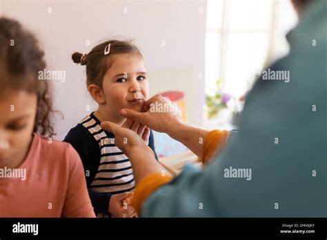 Unrecognizalbe Father Is Cleaning Mouth Of Little Daughter When Eating