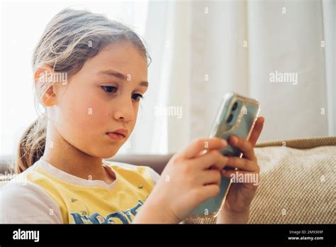 Süßes kleines Mädchen das Technologie Gerät benutzt sitzt auf dem Sofa Ein Mädchen das am