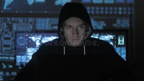 man geek hacker in hood working at computer in cyber security center