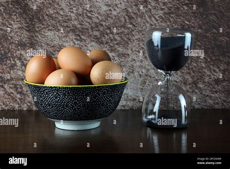 Sand Glass Egg Timer With Bowl Of Fresh Eggs On A Varnished Wooden