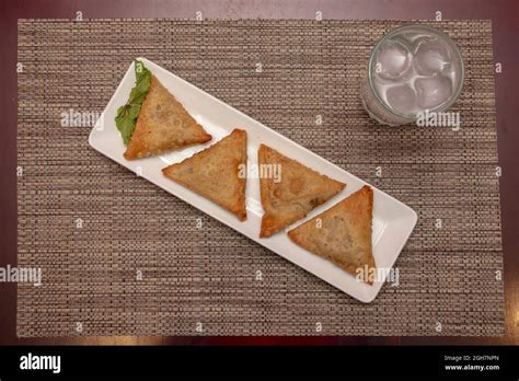 Top View Of Pita Bread Triangles With Minced Meat And A Glass Of Iced Drink On A Red Table Stock