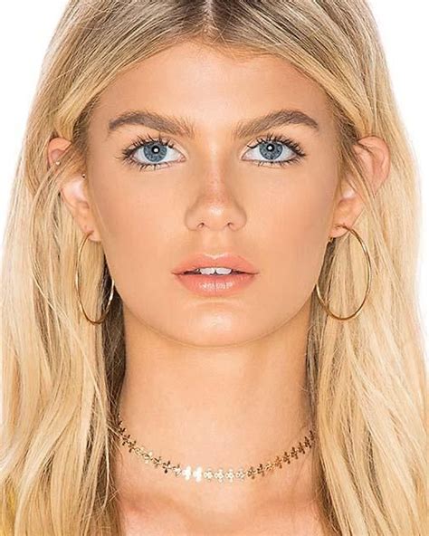 A Woman With Blonde Hair And Blue Eyes Wearing A Choker Necklace And