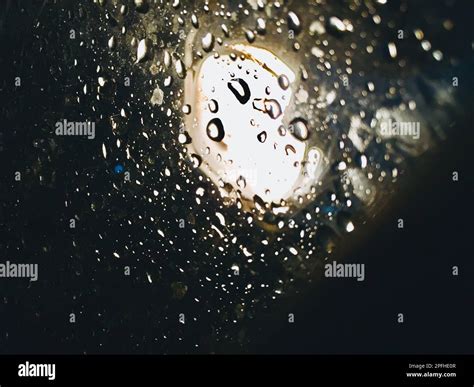 A Close Up Shot Of A Glass Window With Raindrops Cascading Down Its Surface And A Clock In The