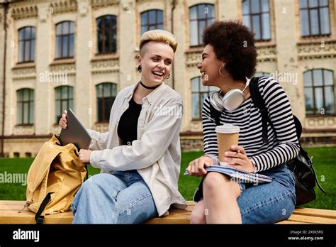 A Young Multicultural Lesbian Couple Chatting On A Bench In A