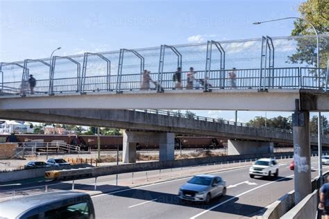 Image Of Pedestrians Crossing Busy Road On Footbridge Overpass