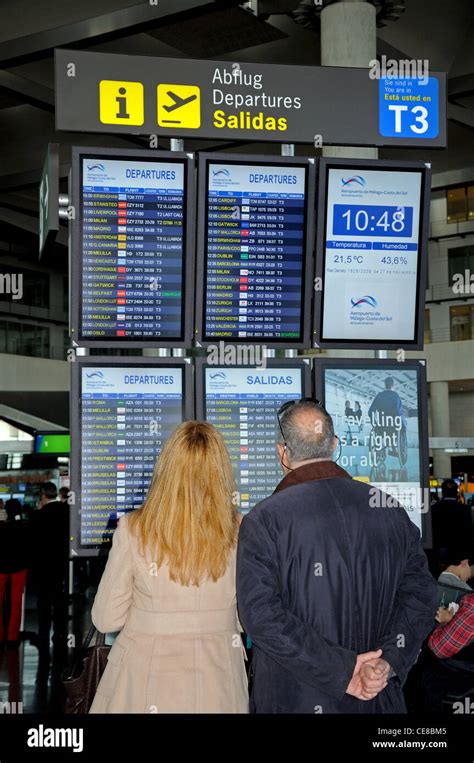 Passengers Looking At Departure Destination Boards In Terminal 3