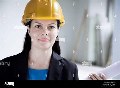 Portrait Of Smiling Architect In A Hardhat Holding A Rolled Up Blueprint Indoors Close Up Stock