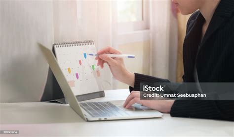 2024년 이벤트 플래너 캘린더 의제 시간표 사무실에 있는 책상에서 전화기로 플래너를 확인하고 책상 달력에 메모를 하는 사업가 작업 계획 이벤트 일정 검사 보기에 대한 스톡