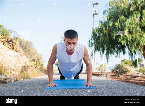 Young Caucasian Man Does Push Ups On His Mat In A Public Park The
