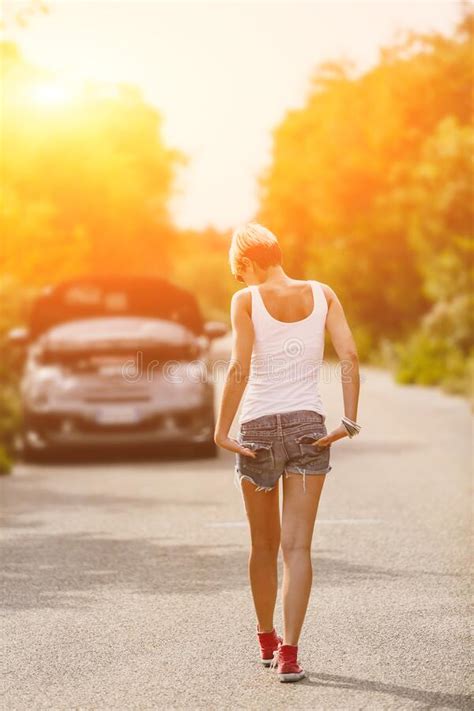 Young Sad Woman Standing Near The Road By The Broken Car In The Middle