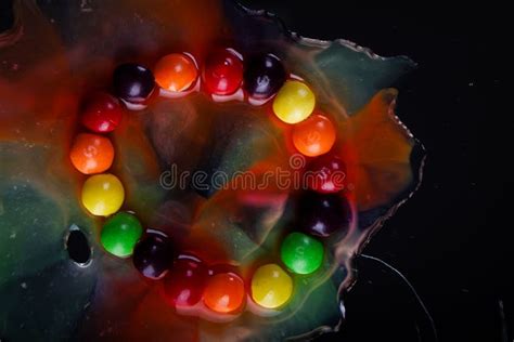 Vibrant Candy Circle Melting On Dark Surface Creating Colorful Puddle