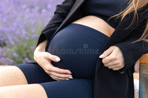 Close Up Of Torso Of Young Pregnant Model Standing In Park And