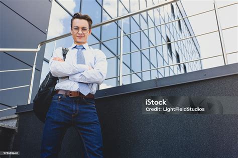 교차 팔으로 서와 사무실 건물 밖에 서 카메라를 보고 잘생긴 젊은 사업가의 낮은 각도 보기 남자 사업가에 대한 스톡 사진 및 기타 이미지 남자 사업가 팔짱 낌 남성