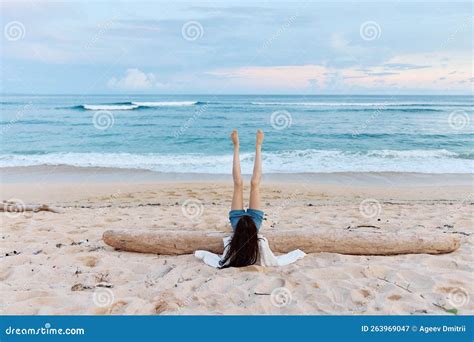 Girl Lying On The Sand With Her Legs Up With Her Back To The Camera On