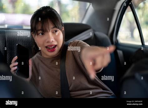 A Happy Young Asian Female Passenger Is Giving Directions To A Taxi