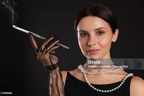 Woman Using Long Cigarette Holder For Smoking On Black Background Stock