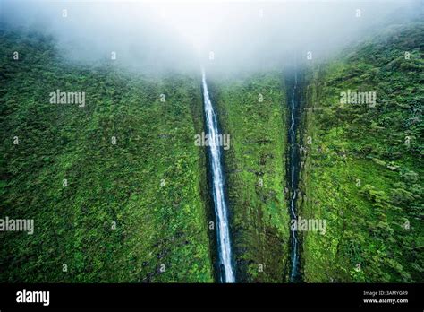 Aerial View Of Lush Tropical Waterfall Cascading Down Misty Cliff At Molokai Twin Falls Maui