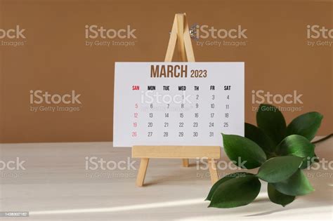 2023년 3월 나무 스탠드에 달 달력입니다 녹색 분기 옆에 있는 바탕 화면에 며칠과 주가 있는 흰색 용지입니다 새해의 개념 2023년에 대한 스톡 사진 및 기타 이미지