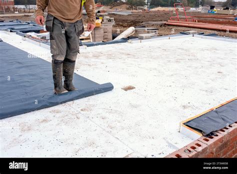 Builder Placing Polystyrene Insulation Boards On Waterproofing Membrane During Floor